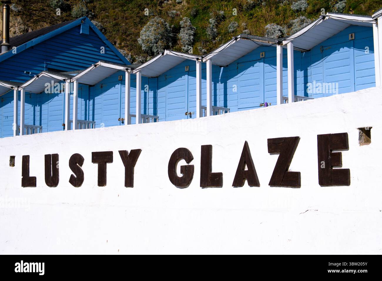 Lusty Glaze sign with iconic blue beach huts in Newquay, Cornwall, on a ...