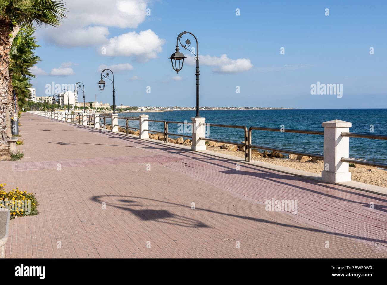 Coastal promenade with palm trees and sandy beach in Mediterranean town ...