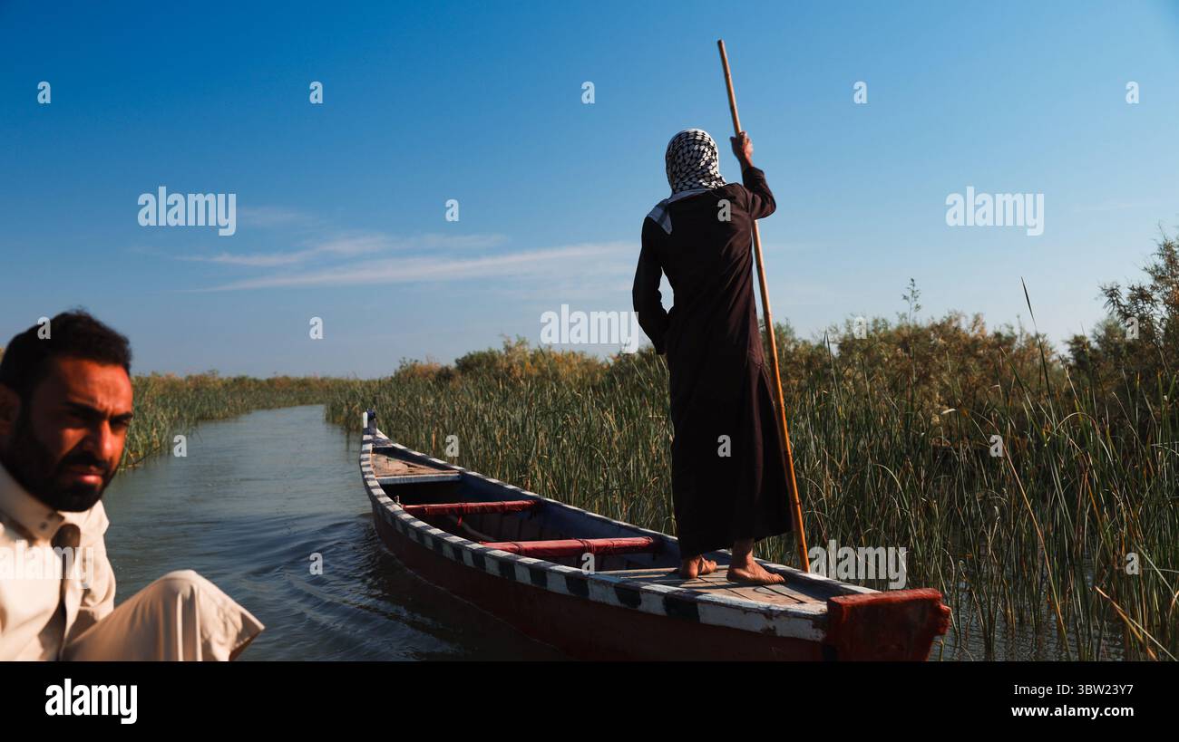 Two individuals navigate a traditional boat through the lush ...