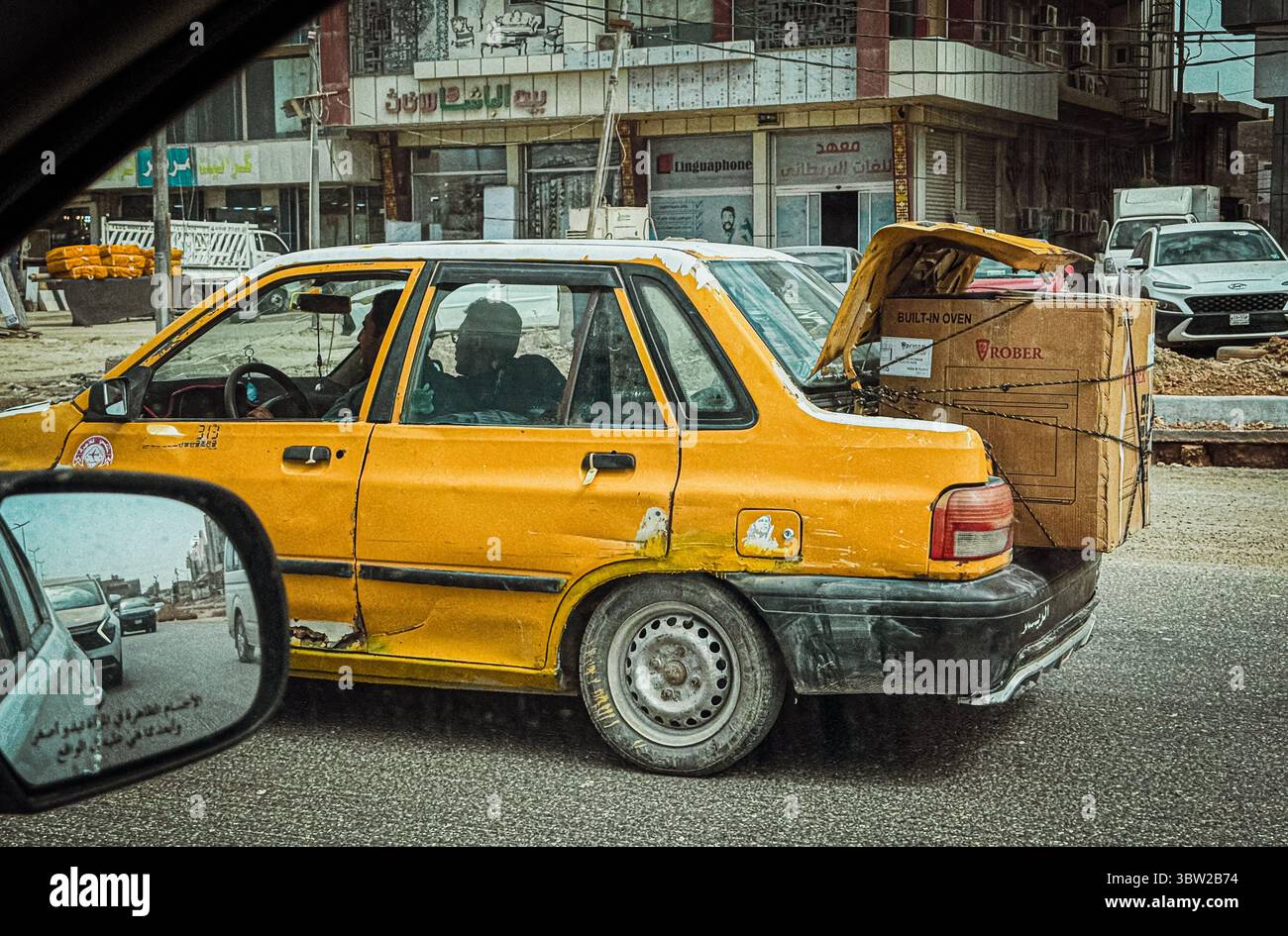 A yellow taxi navigates through traffic in Baghdad, Iraq, carrying ...