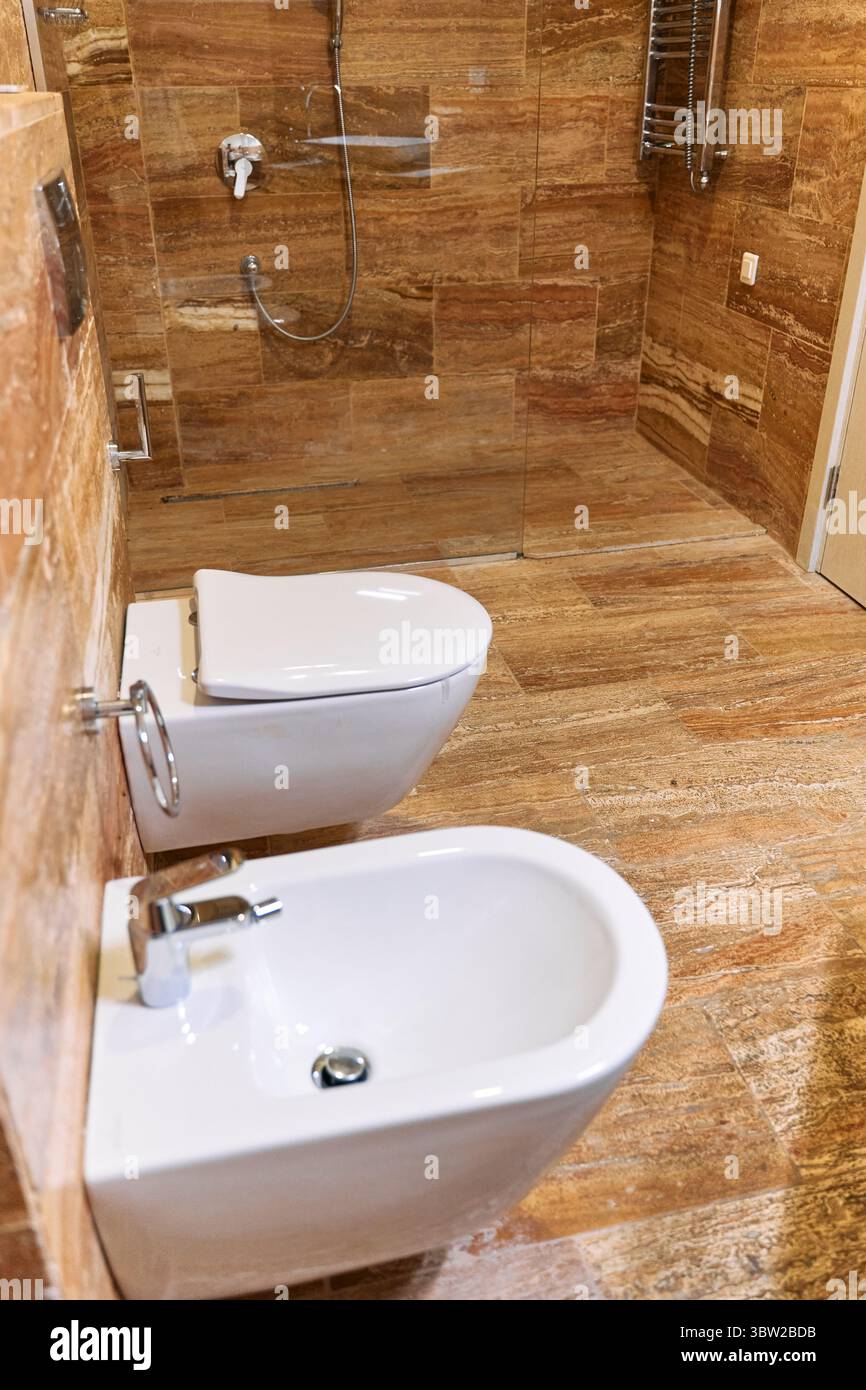 A modern bathroom designed with natural stone tiles showcases a toilet ...