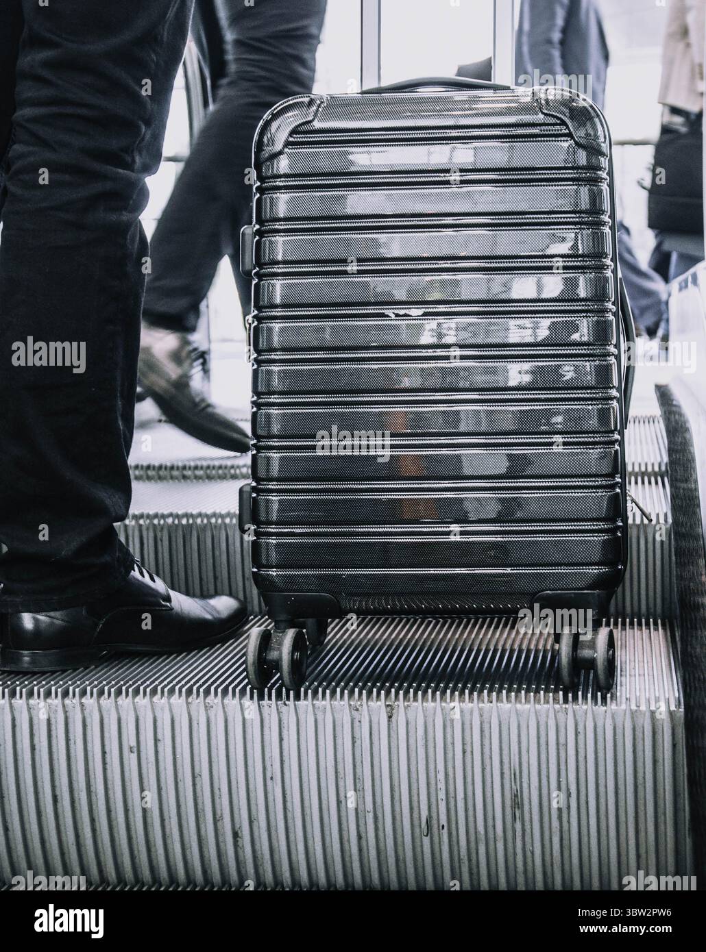 Stylish grey suitcase with wheels on escalator moving stairs near ...