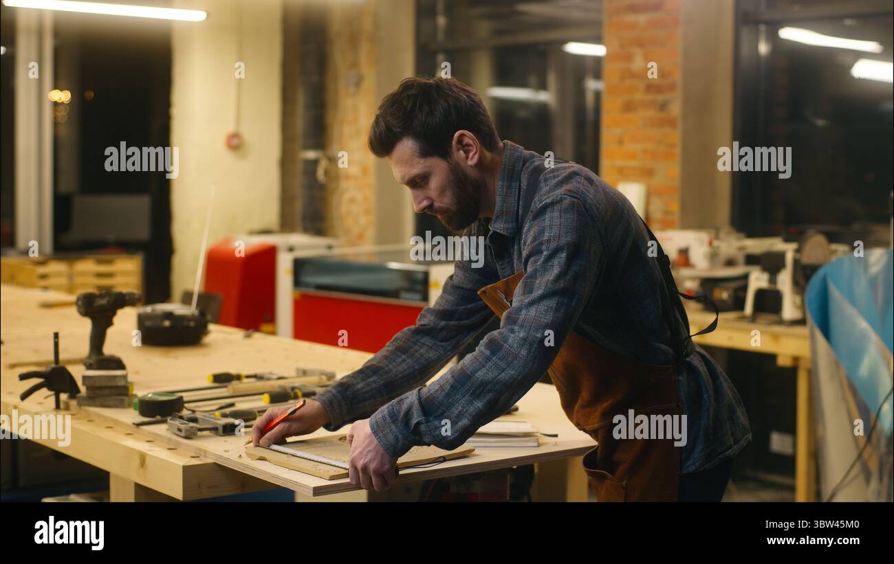 Professional pensive Caucasian carpenter guy worker measure hardwood ...