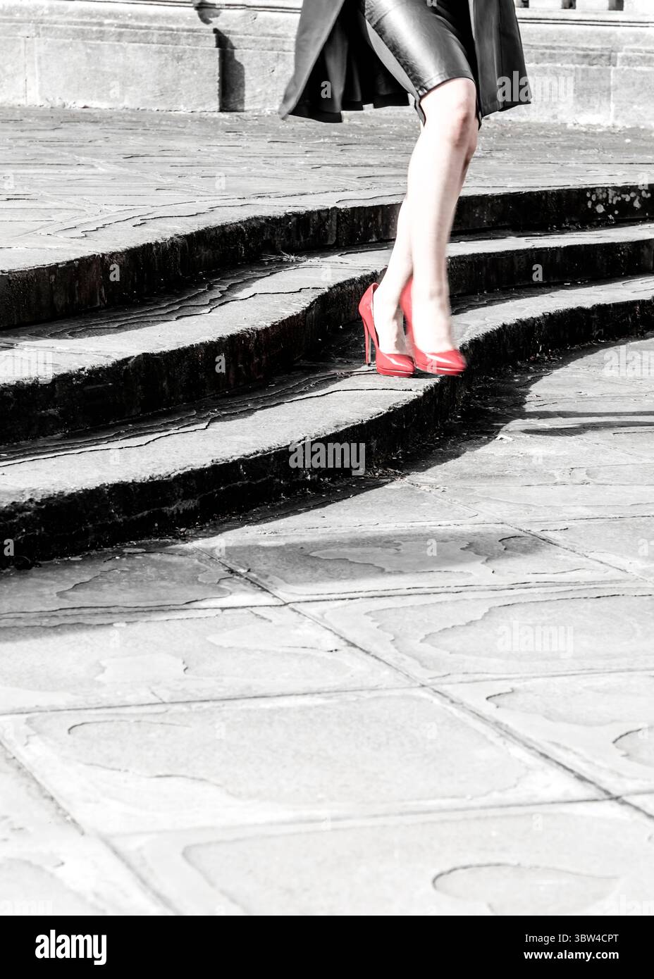 A person wearing red high heels is walking down a set of stone steps ...
