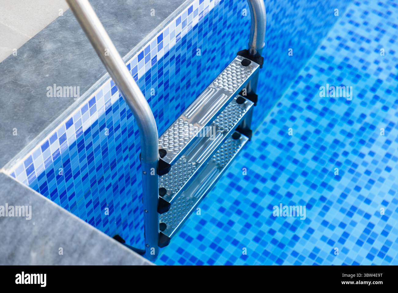 Close-up view of a blue-tiled swimming pool featuring a stainless steel ...