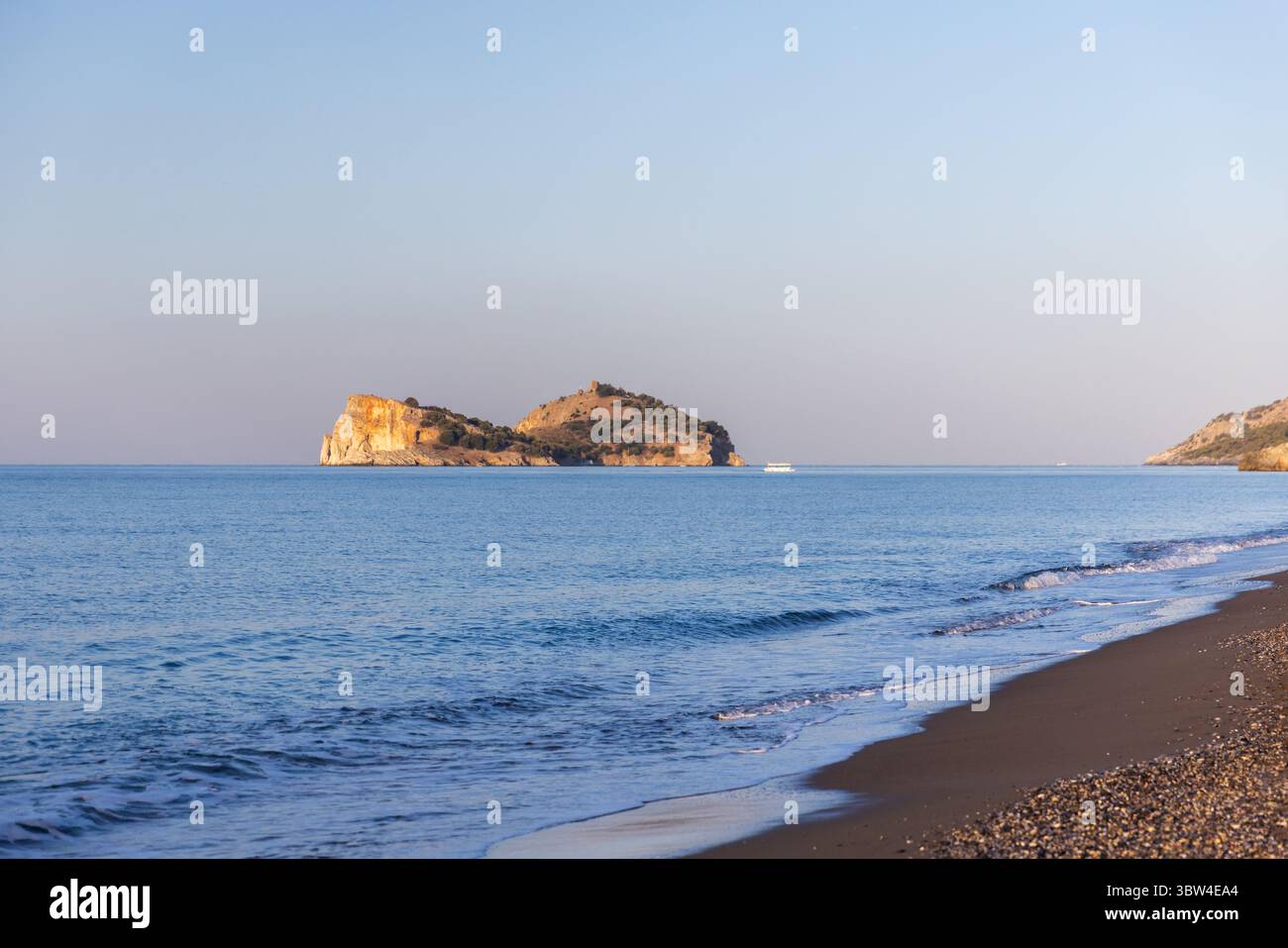 A serene sandy beach overlooks calm turquoise sea waters with a small ...