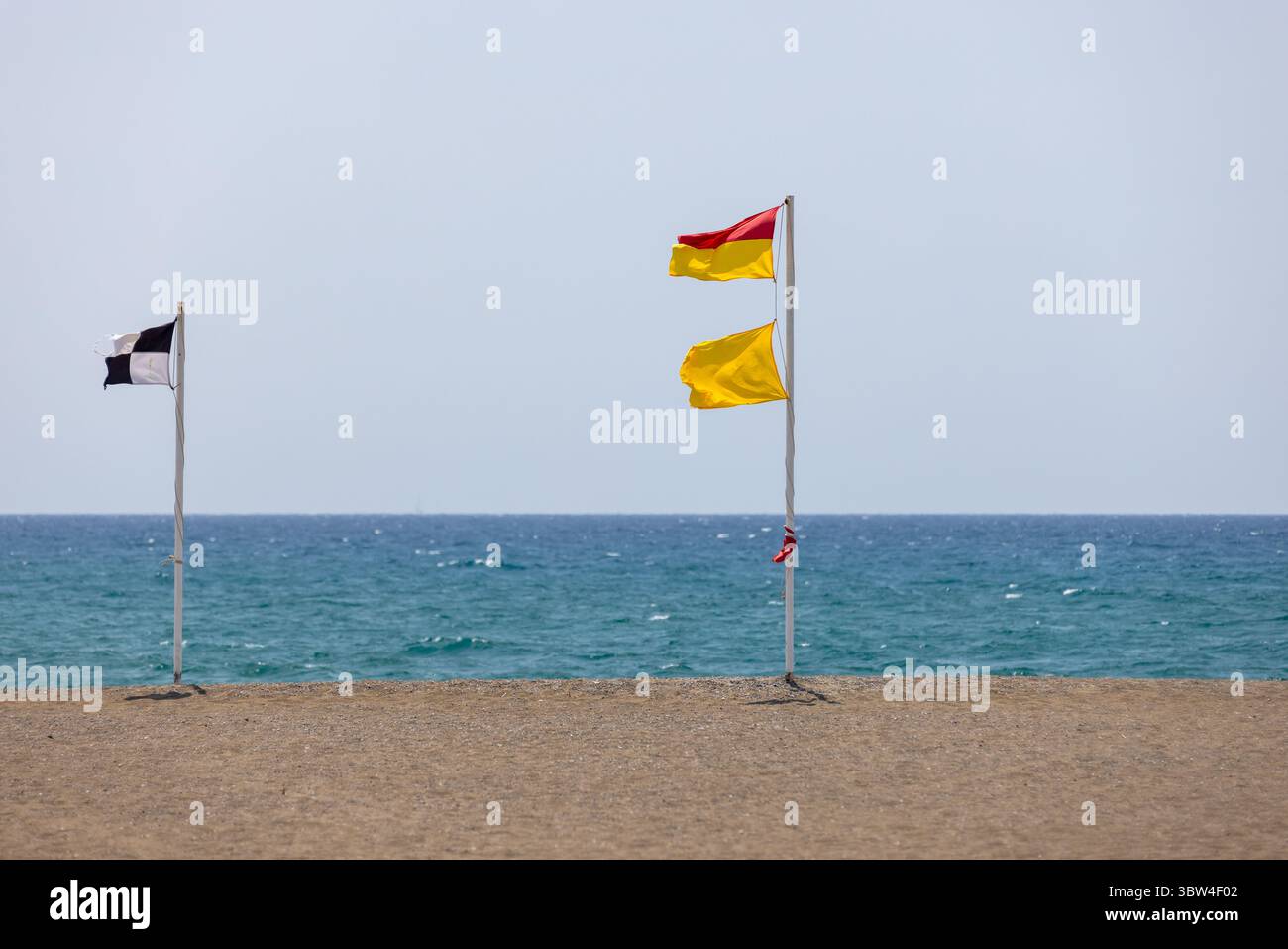 Vibrant colored flags flutter over a tranquil sandy beach by a clear ...