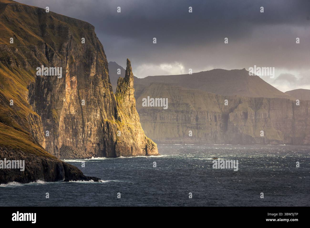 View of dramatic cliffs meet the churning sea under a brooding sky ...