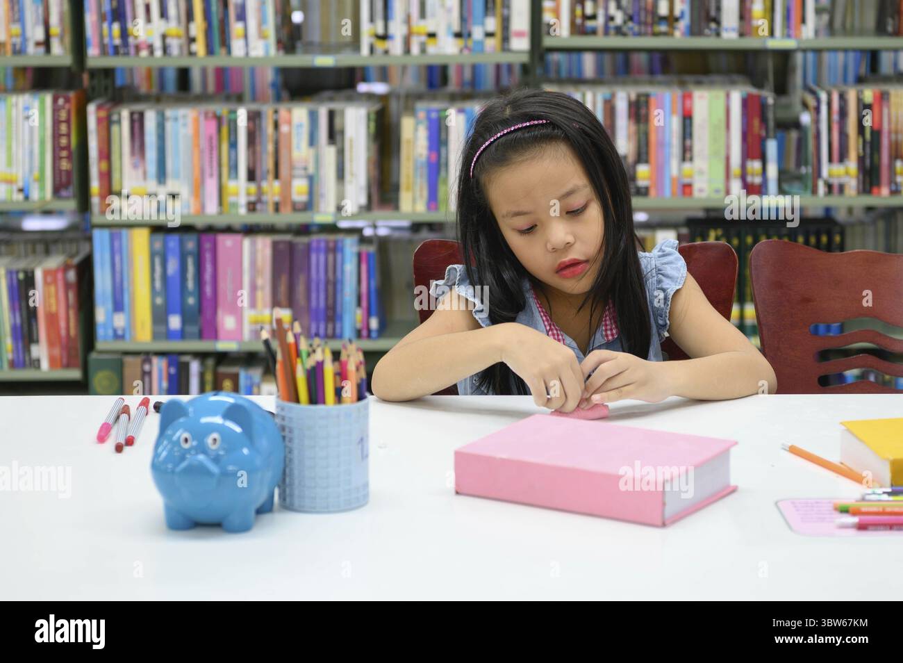 Asian girl folding and crafting paper in library during art class ...