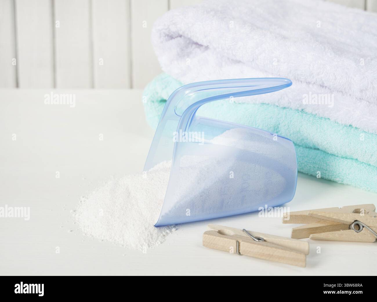 Stack of white and blue fluffy bath towels, washing powder in measuring ...