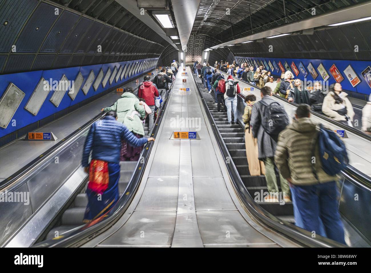 Crowded subway escalator with commuters traveling through a busy ...