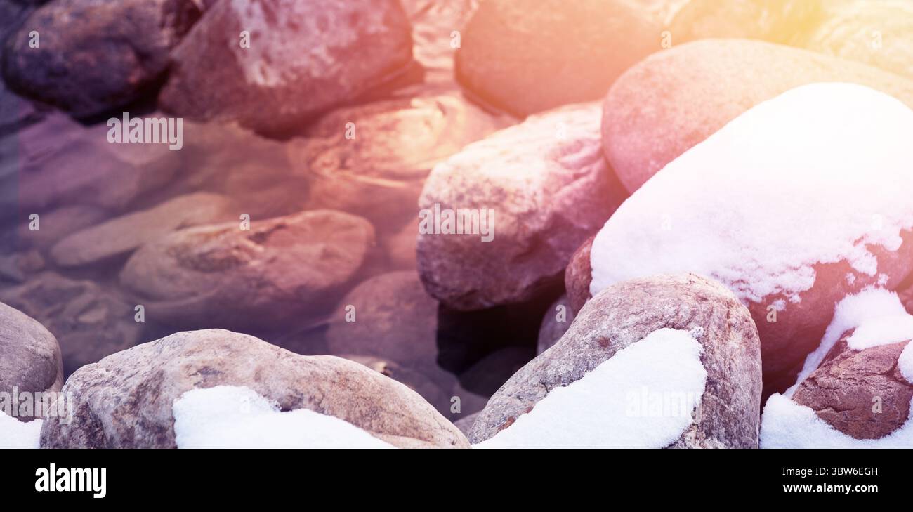 Rocks covered with snow on stream Stock Photo - Alamy