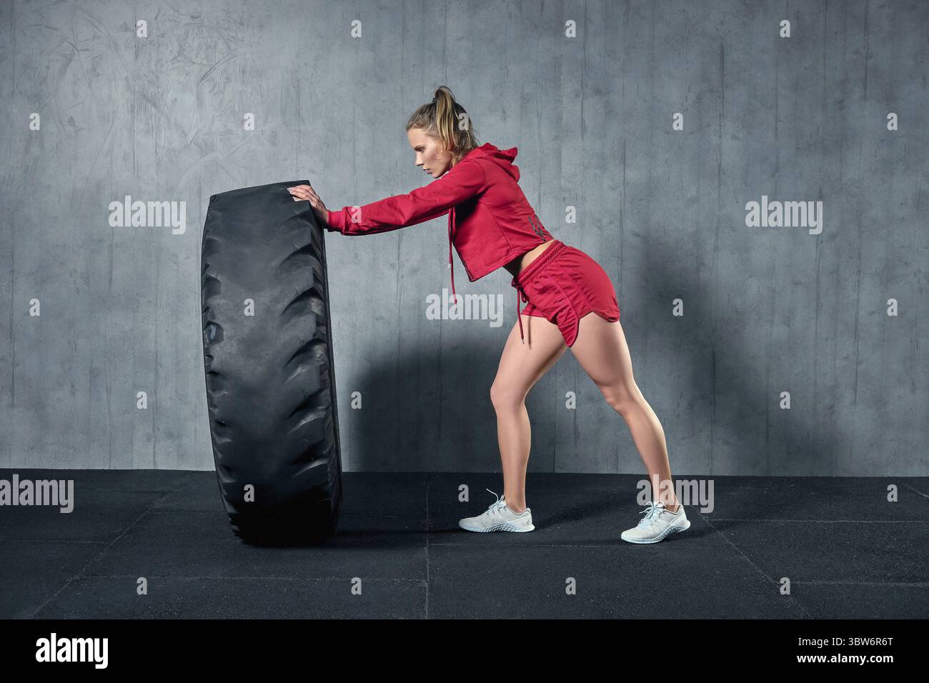 Fitness woman flipping wheel tire in gym. Fit female athlete working ...