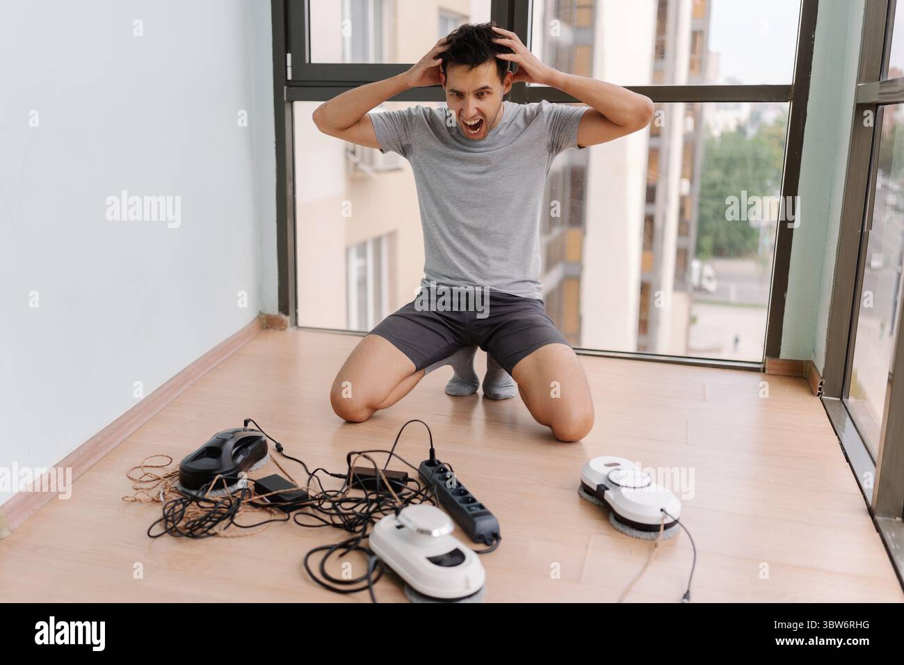 Stressed screaming window cleaner male kneeling on balcony, gripping ...