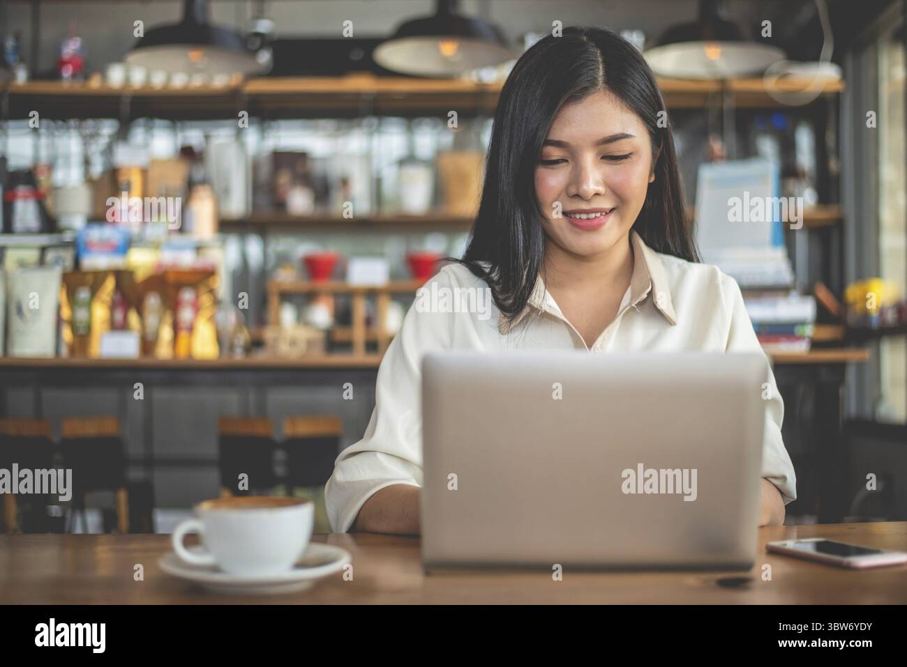 Asian female freelancer smiling when using laptop in cafe. Business and ...
