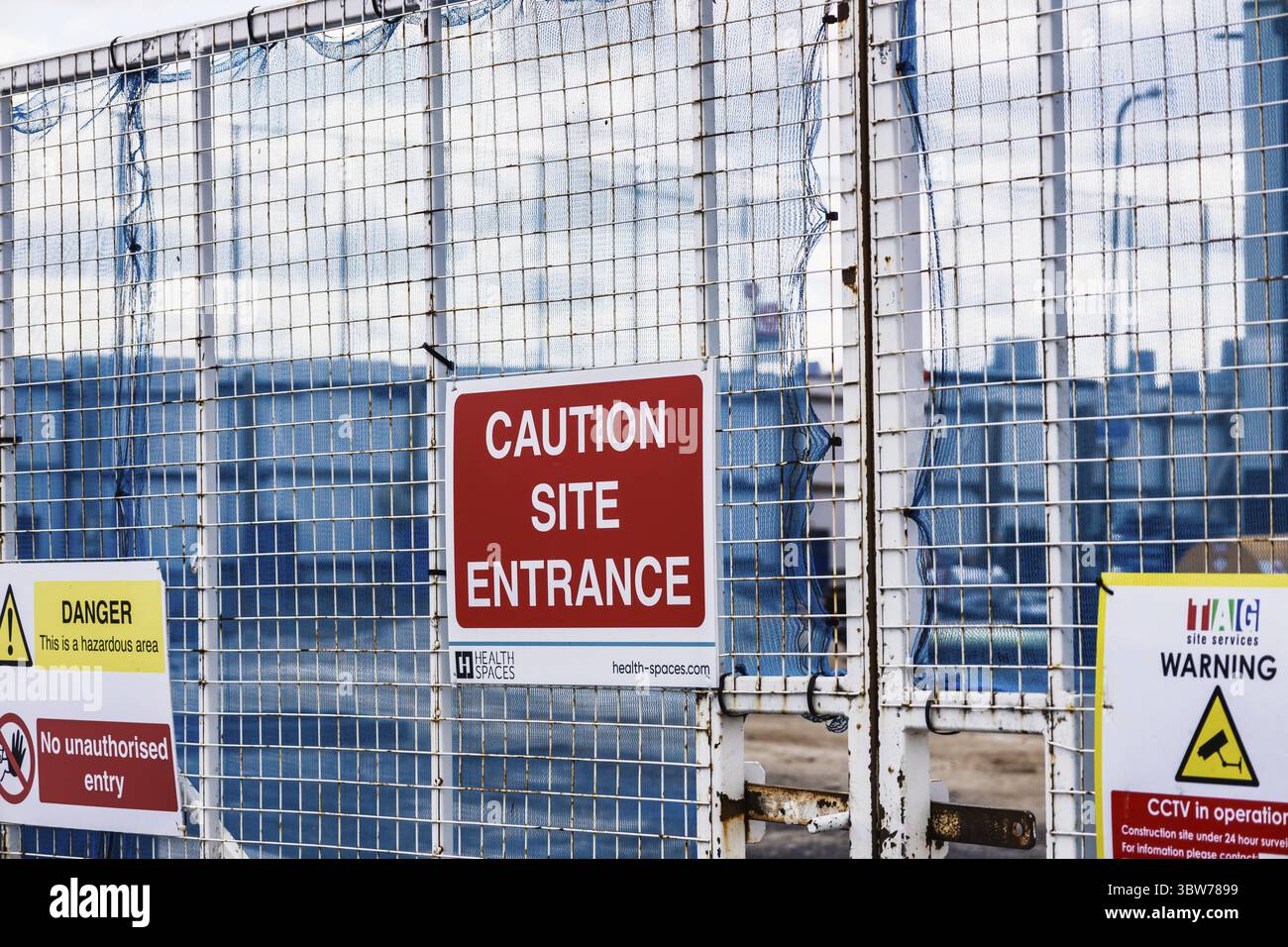 Construction site entrance featuring metal fencing and multiple caution ...