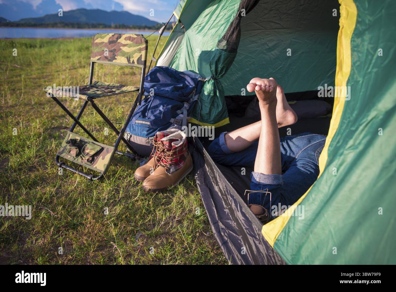 Close up of woman legs relaxing in camping tent with mountain lake and ...