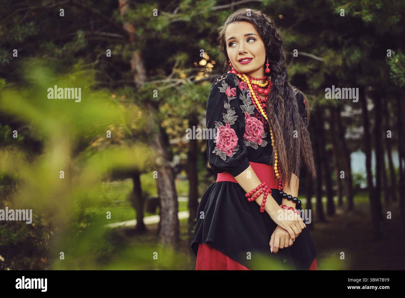 Elegant brunette woman with a long dark hair, in a black and red ukrainian embroidered authentic ...