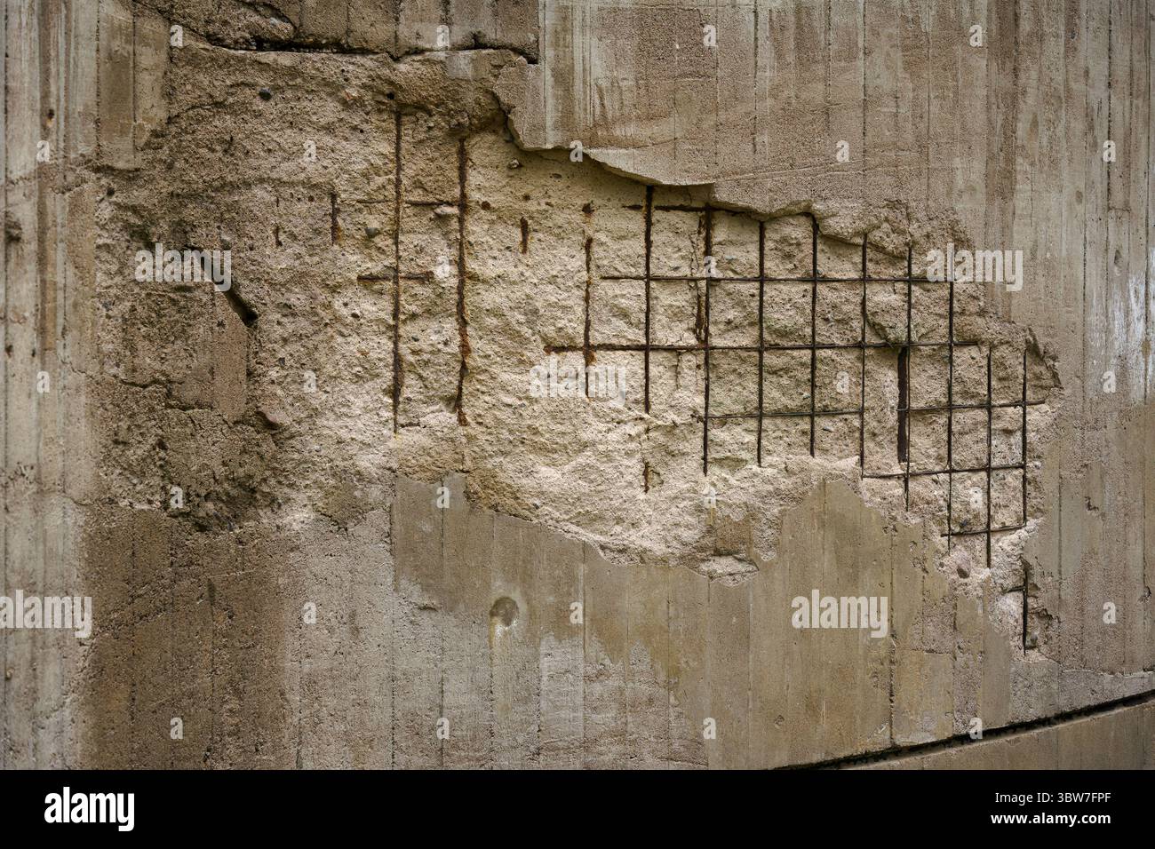Concrete wall with surface erosion, revealing internal rebar structure ...