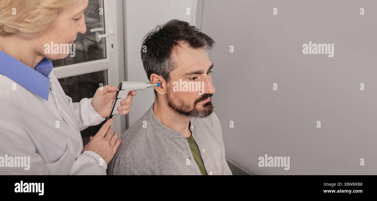 Experienced audiologist with tympanometer probe doing tympanometry ...