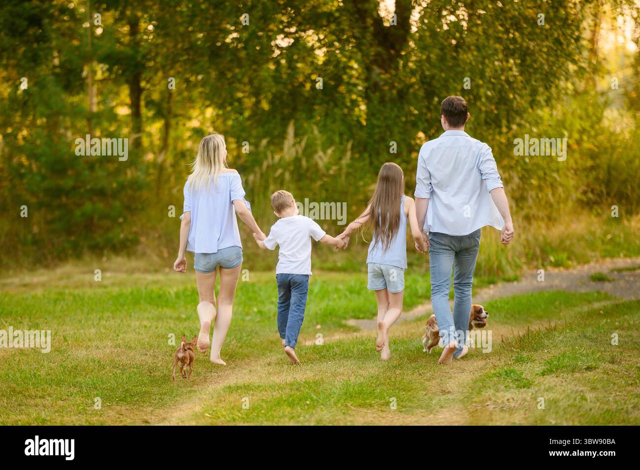 Mom, dad, boy, girl enjoying country vacation, holding hands, running ...