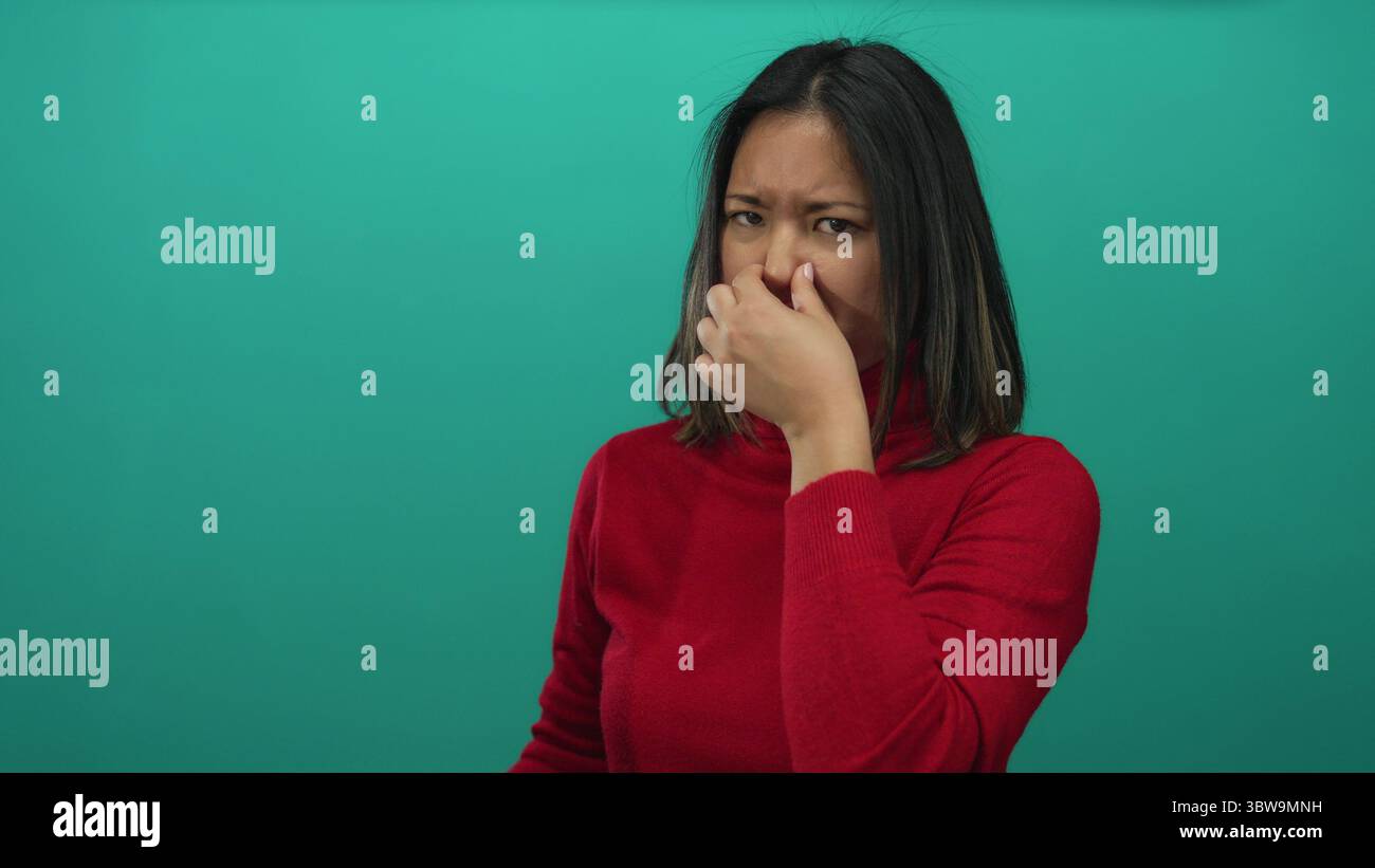 Woman expressing disgust against isolated green background, wearing red ...