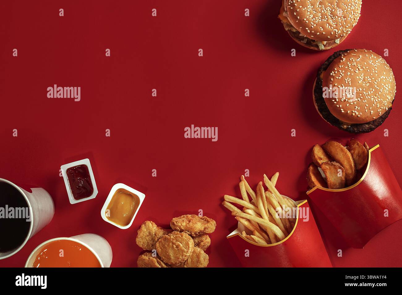 Two hamburgers and french fries, sauces and drinks on red background ...