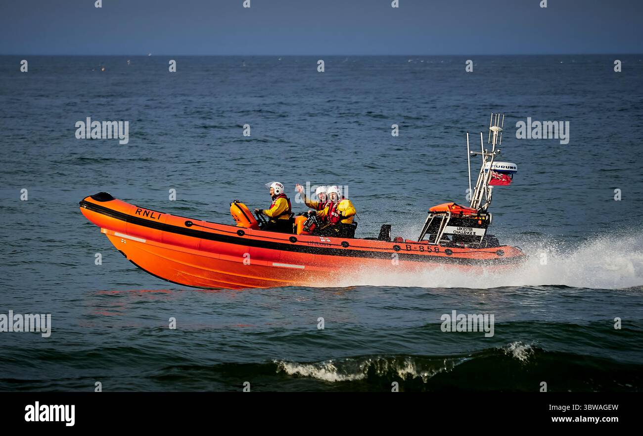 Redcar RNLI inshore lifeboat side view with three crew waving Stock ...