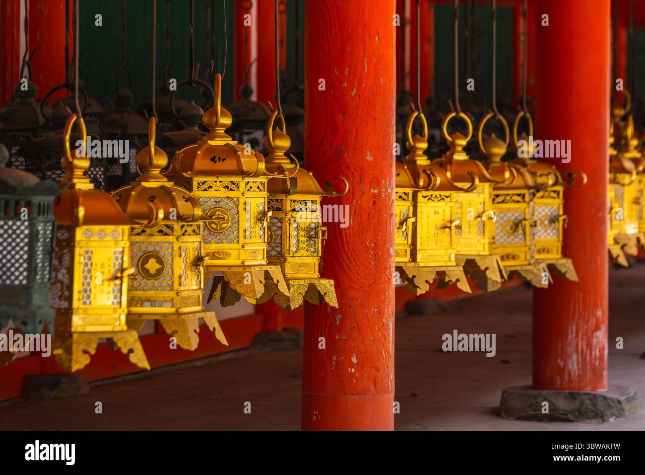 Intricate gold lanterns hang from the ceiling of a vibrant red temple ...