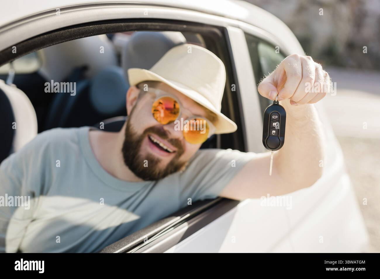 Autofahrer Mann laechelnd zeigt neue Autoschluessel und Auto. Bearded ...