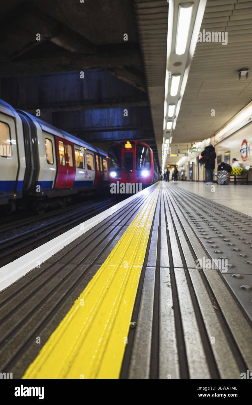 London Underground train arriving at a station platform. Focus on the ...