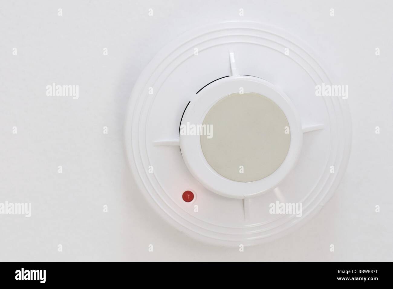 A smoke detector hangs on the white ceiling. Fire prevention device in ...