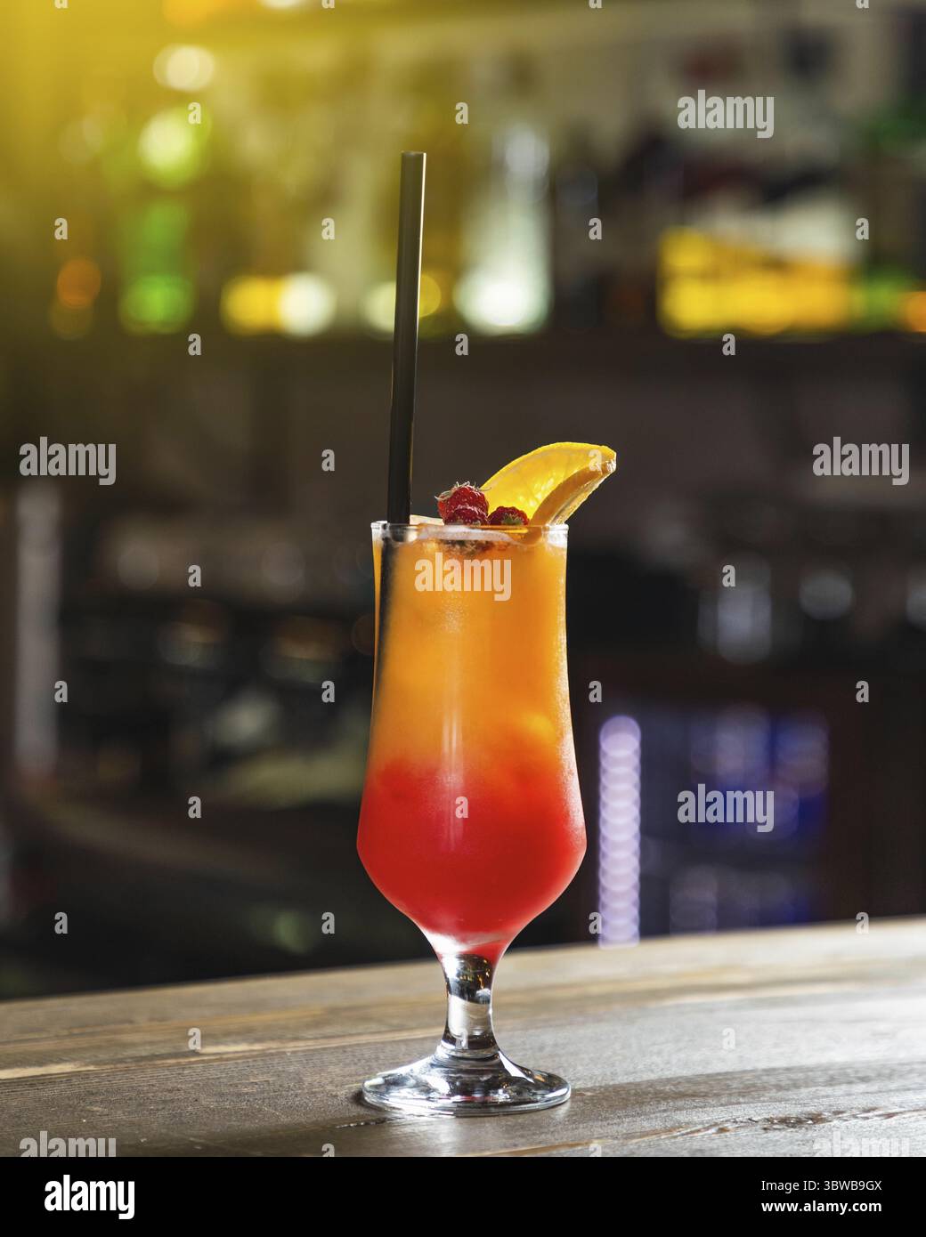Colorful cocktail is standing on the bar counter with a blurry bar ...