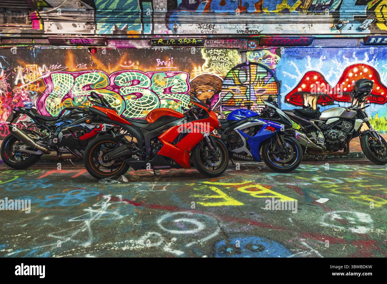 A row of motorcycles parked in front of a vibrant graffiti wall ...
