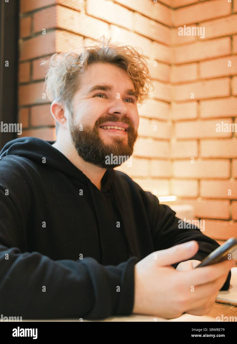 Baertiger gluecklicher Mann laechelnd Portraet im Cafe oder Cafe sitzen ...