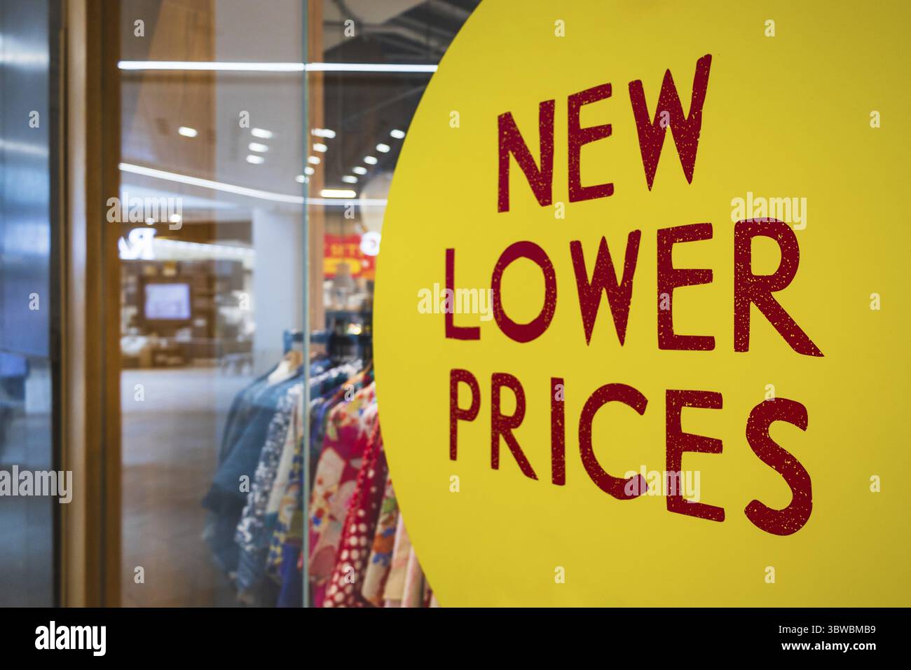 Eye catching yellow sign in a shop window promoting new lower prices ...