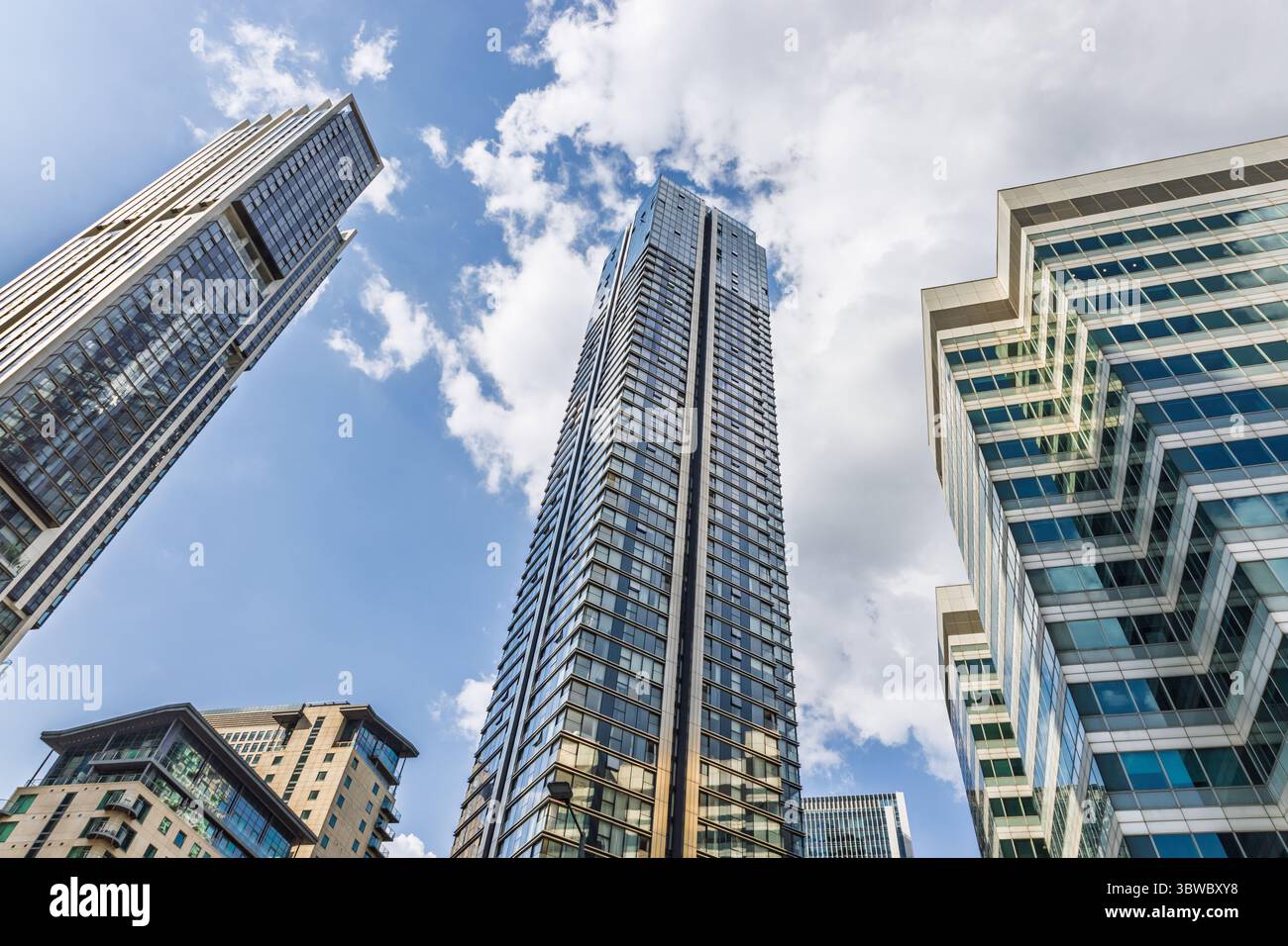 Low angle view of ultra modern glass skyscraper soaring into blue sky ...