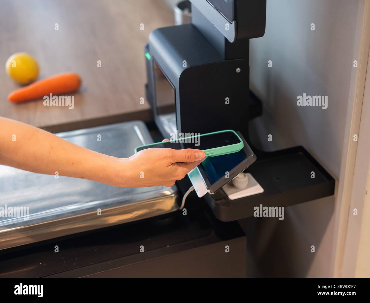 A woman pays using her smartphone at a self-checkout Stock Photo - Alamy
