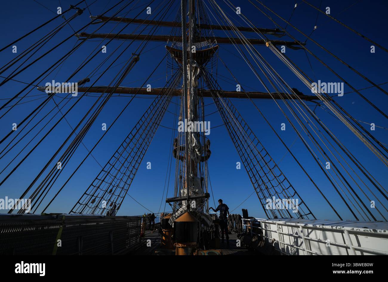 A member of the U.S. Coast Guard walks on the upper deck of the Barque ...