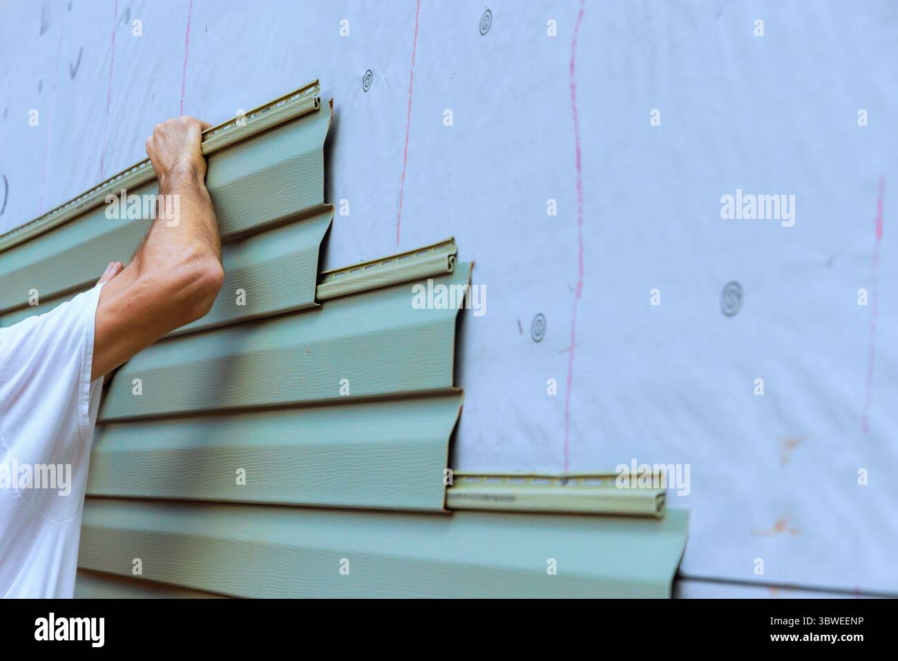 Construction worker carefully places installing new pvc vinyl siding ...
