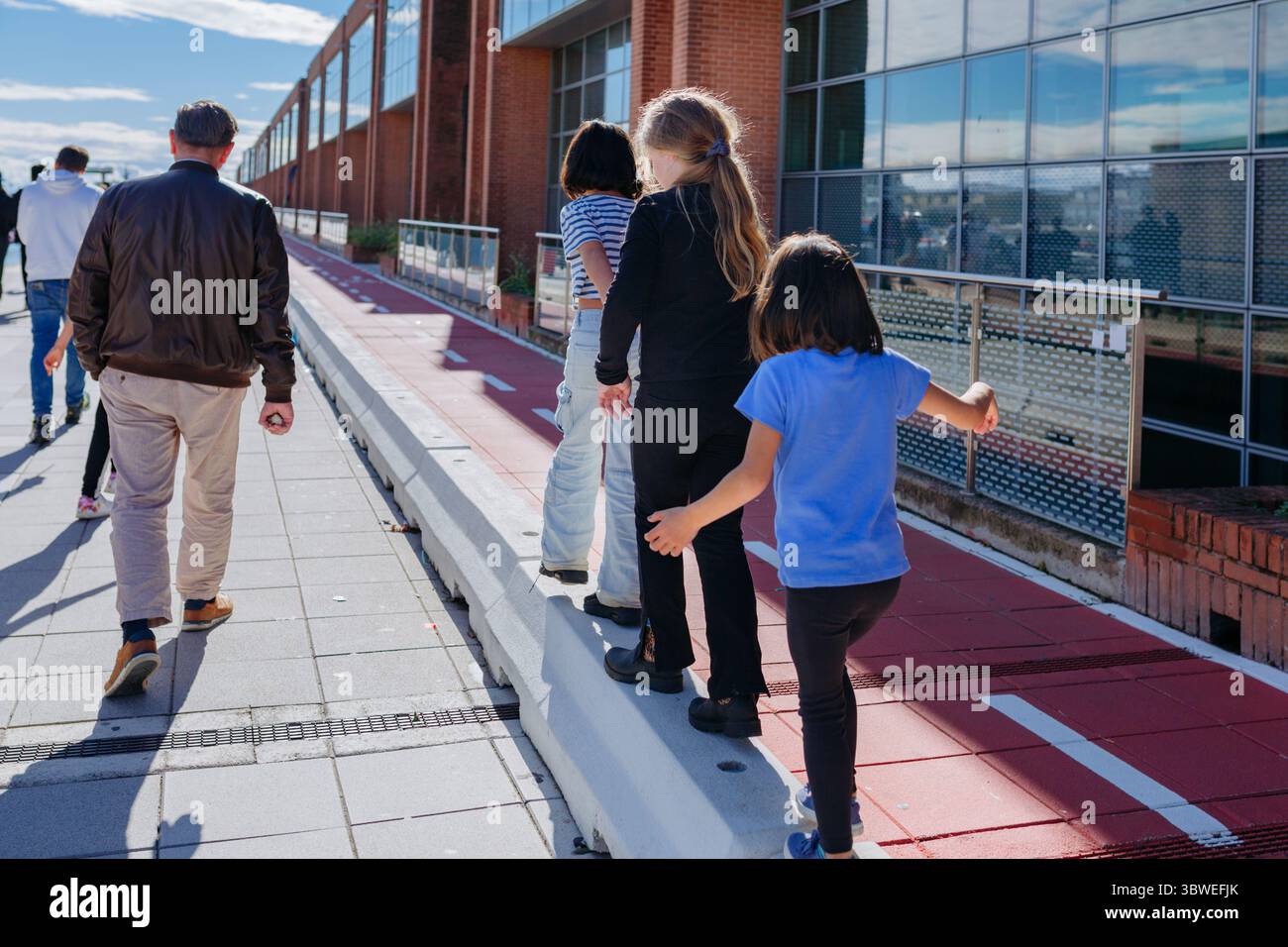 a group of four girls walking next to a father in a city of Venice ...