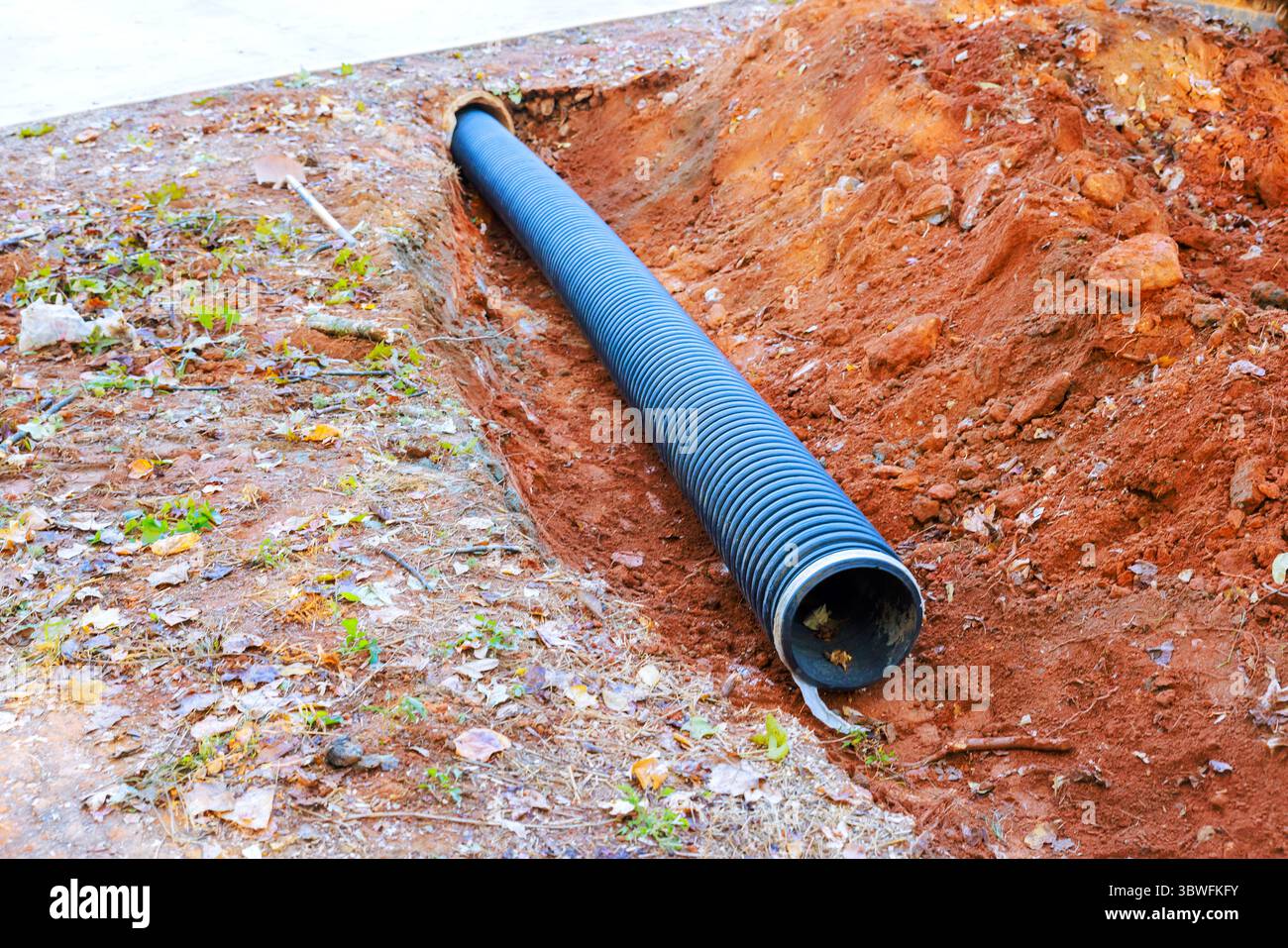 Excavation site with newly installed drainage pipe positioned in trench ...