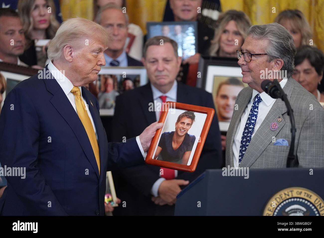 President Donald Trump, left, holds up a photo Greg Swan's son Drew ...