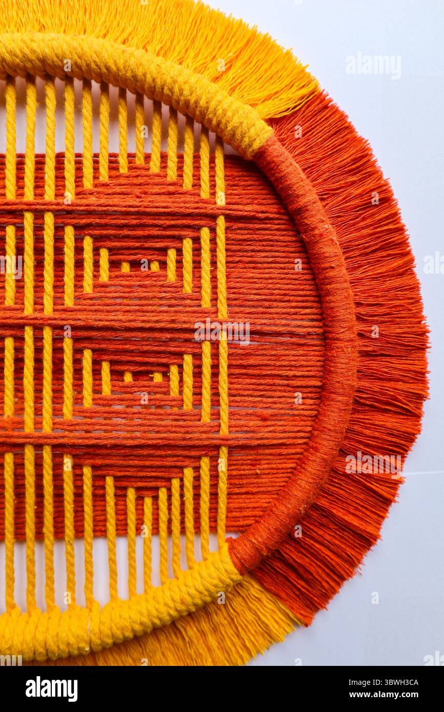 Colorful circular macrame wall hanging in orange and yellow yarn with ...
