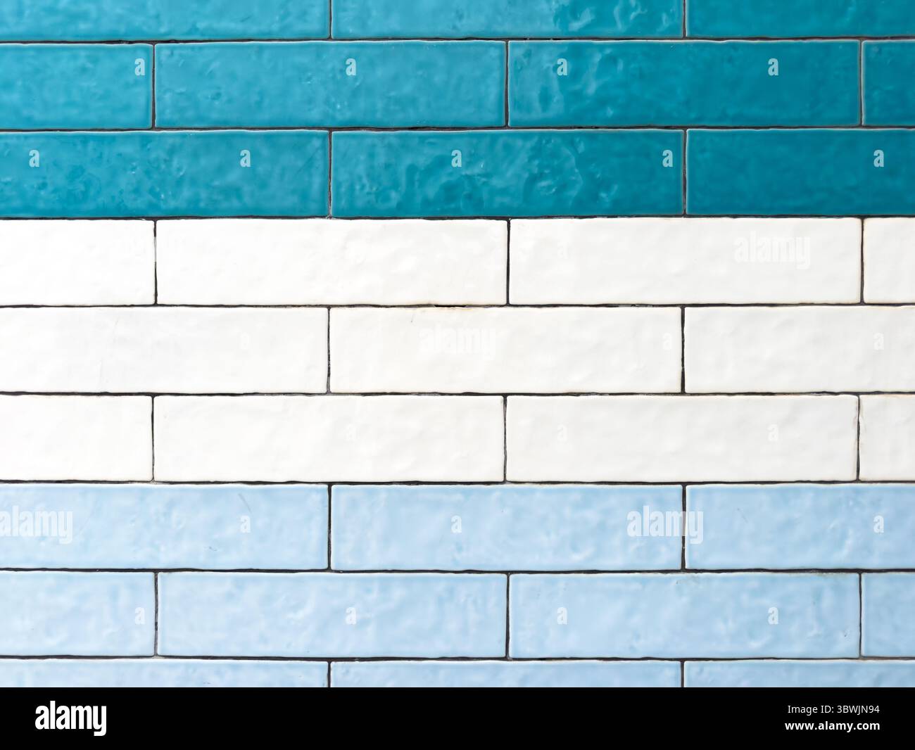 A wall features three distinct horizontal bands of rectangular tiles ...