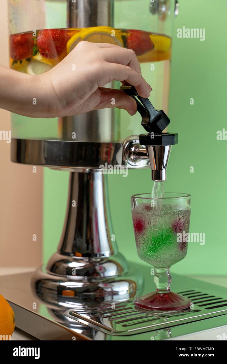 Pouring fruit-infused water from a beverage dispenser. Refreshing detox ...