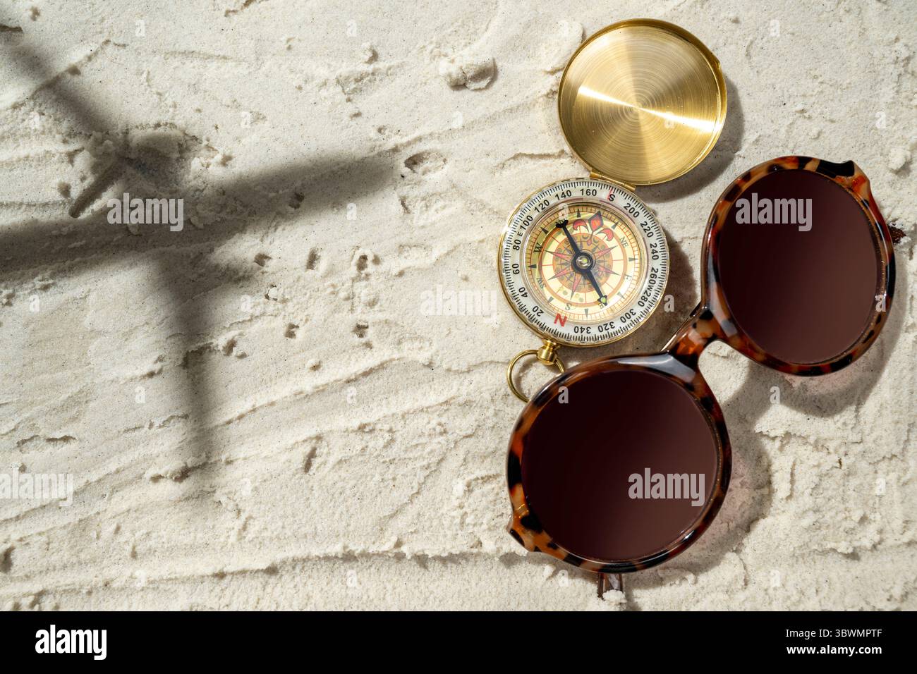 Compass and sunglasses with the shadow of an airplane flying over a ...