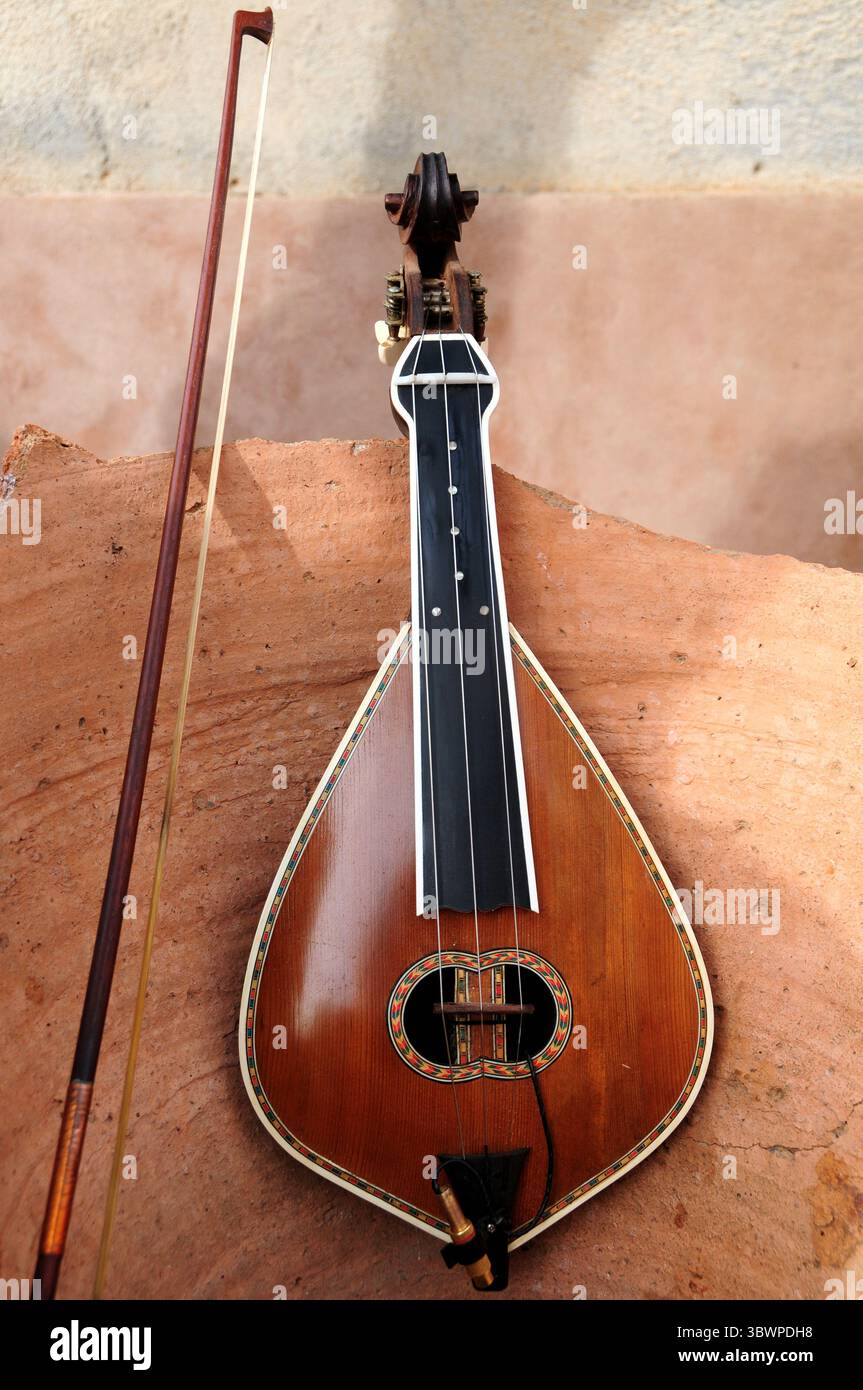 Cretan lyre with its bow, resting on an old clay pot, in the courtyard ...