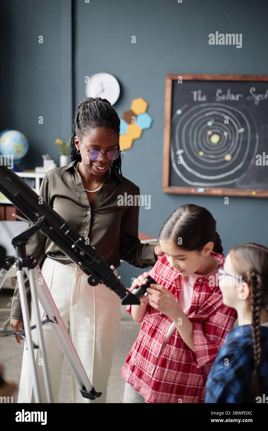 Vertical shot of Black woman teaching two Caucasian girls using ...