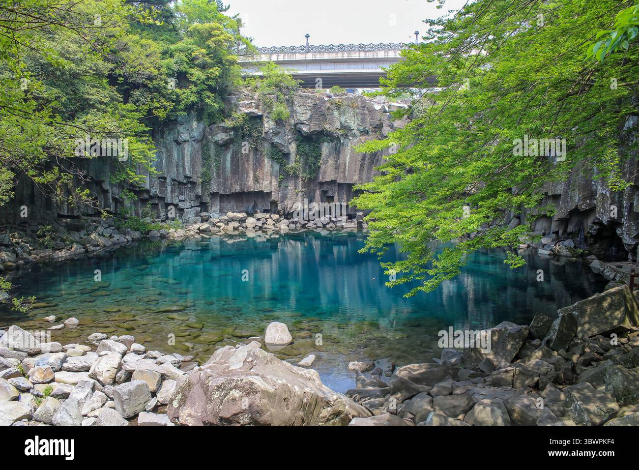 Clear turquoise water surrounded by columnar basalt cliffs and lush ...